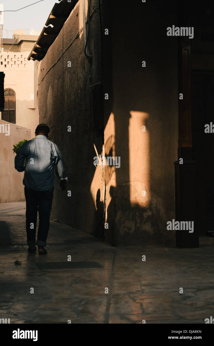 Lonely man walking between the shadows in the narrow streets of Deira ...