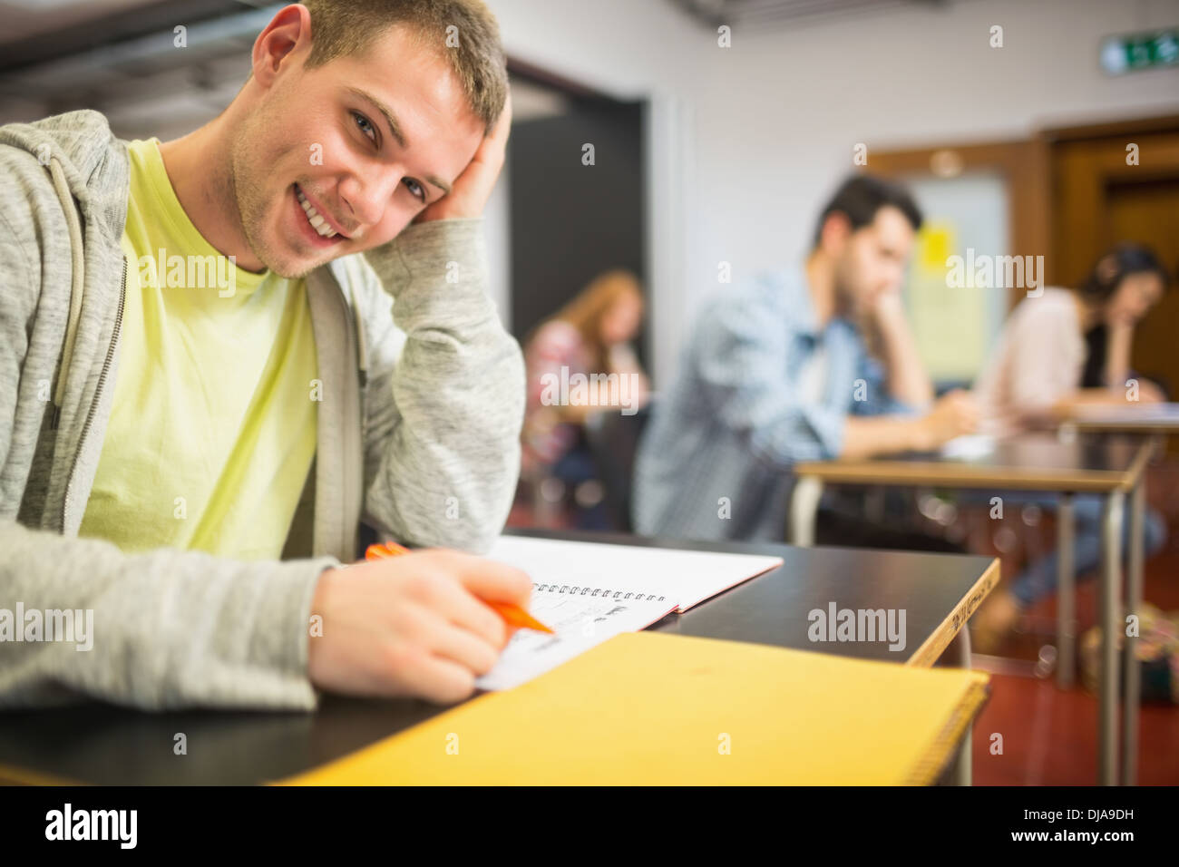 Smiling male student with others writing notes in classroom Stock Photo ...