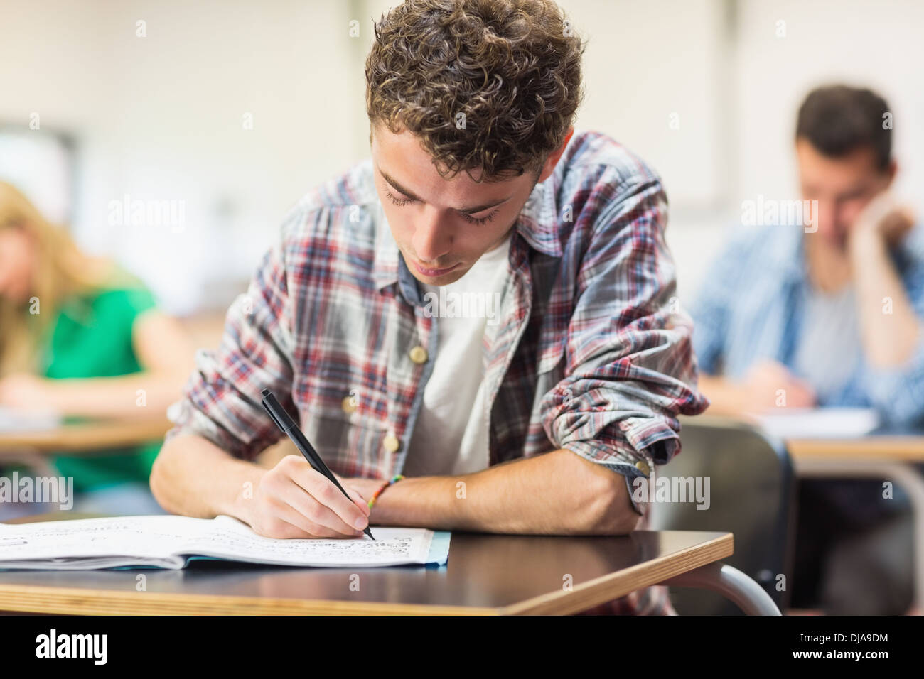 Male student with others writing notes in classroom Stock Photo - Alamy