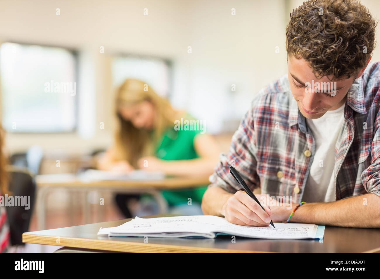 Student with others writing notes in classroom Stock Photo - Alamy