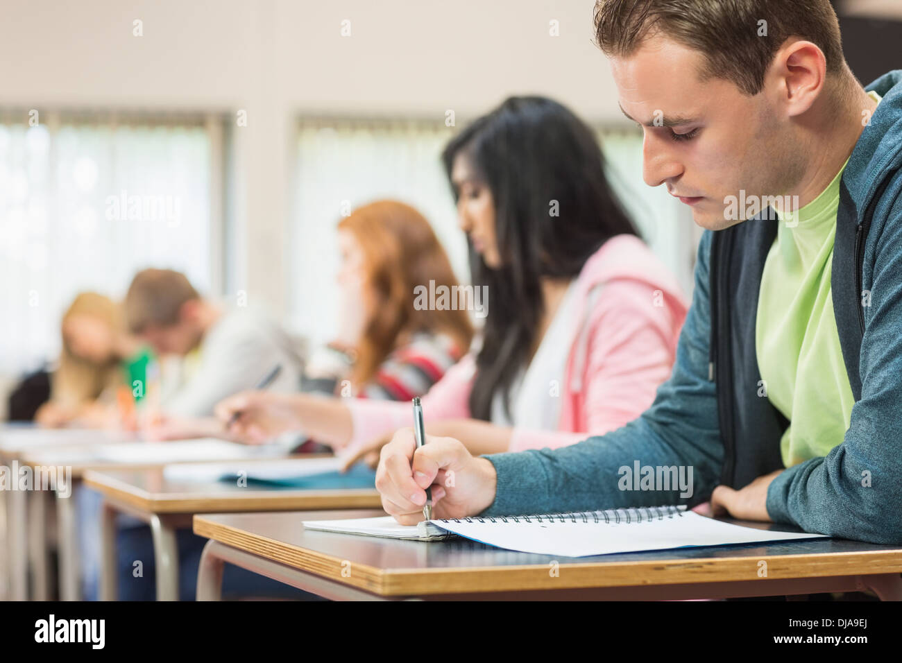 Young students writing notes in classroom Stock Photo - Alamy