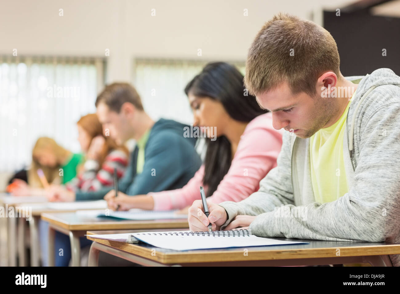 Young students writing notes in classroom Stock Photo - Alamy