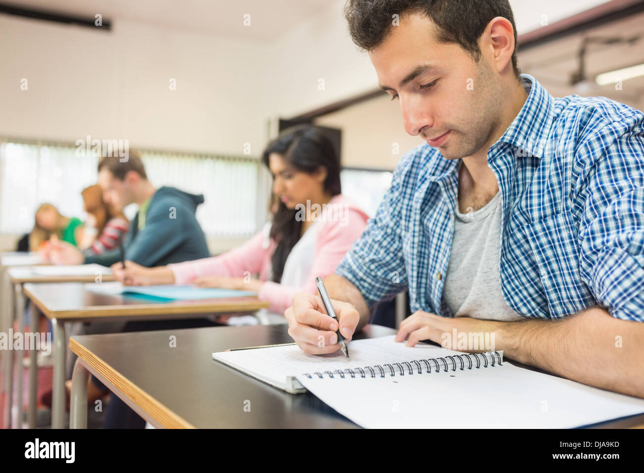 Young students writing notes in classroom Stock Photo - Alamy