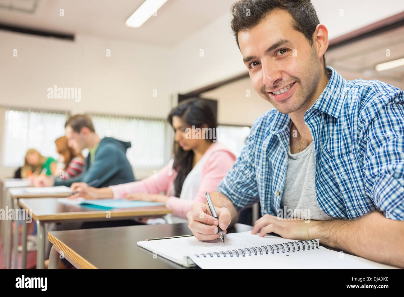 Smiling male student with others writing notes in classroom Stock Photo ...