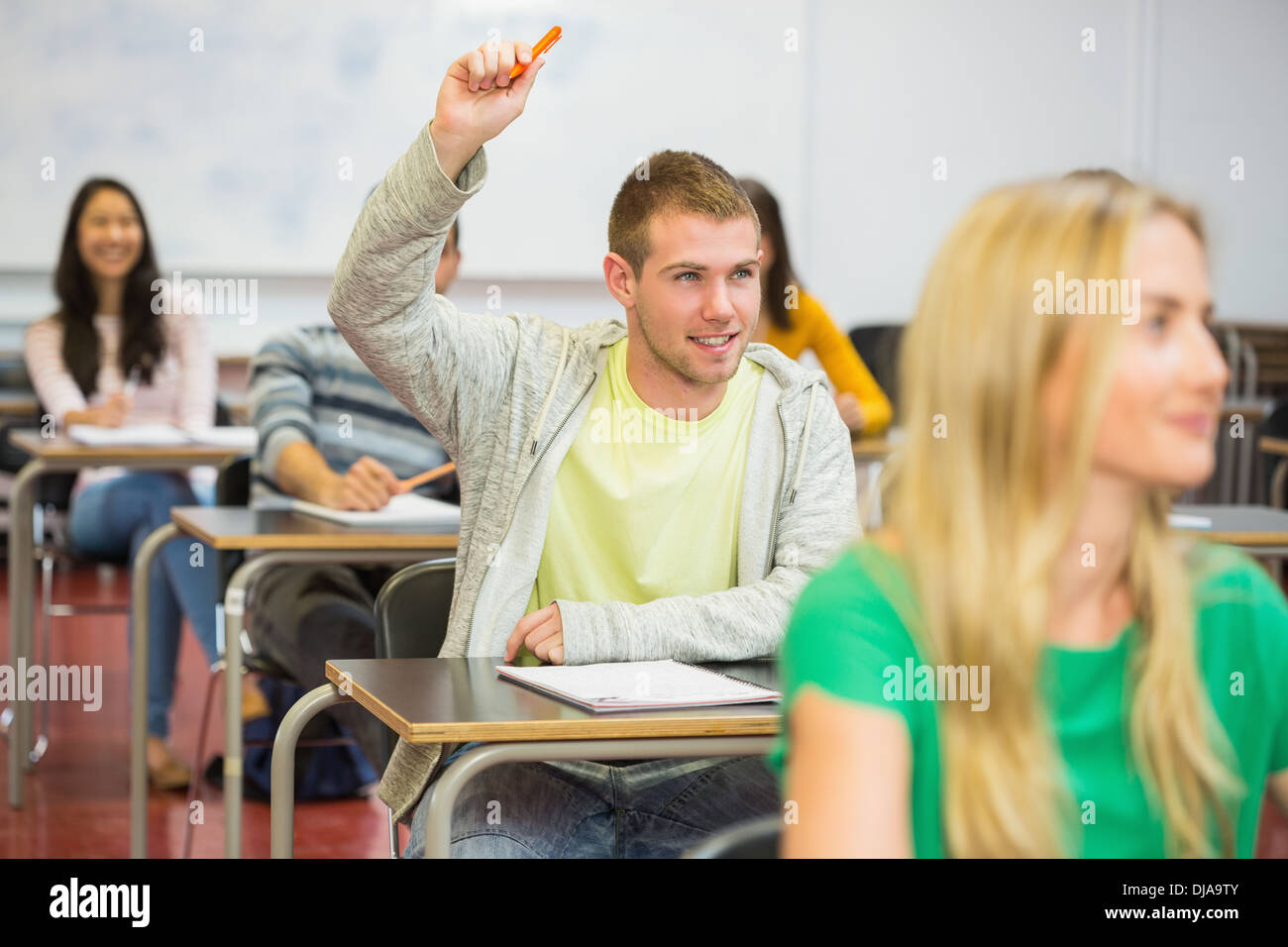 Male student raising hand by others in classroom Stock Photo - Alamy