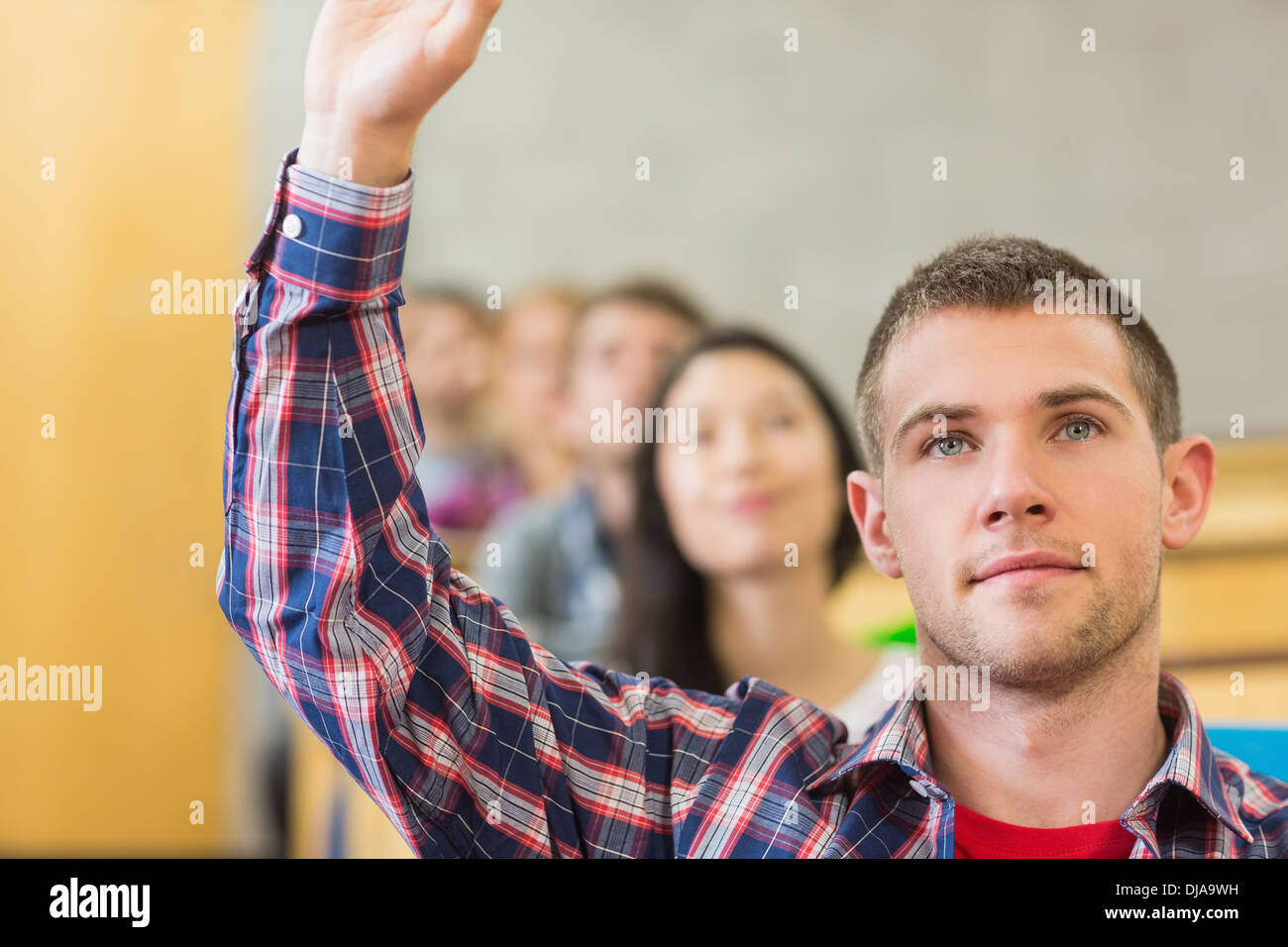 Close up of a male student raising hand by others in classroom Stock ...