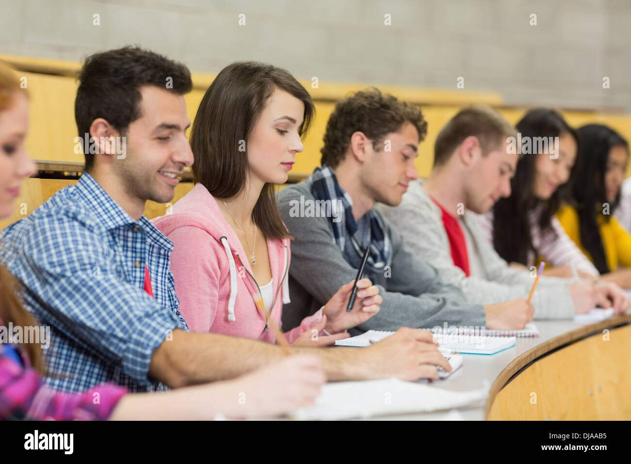 Students writing notes in a row at the lecture hall Stock Photo - Alamy