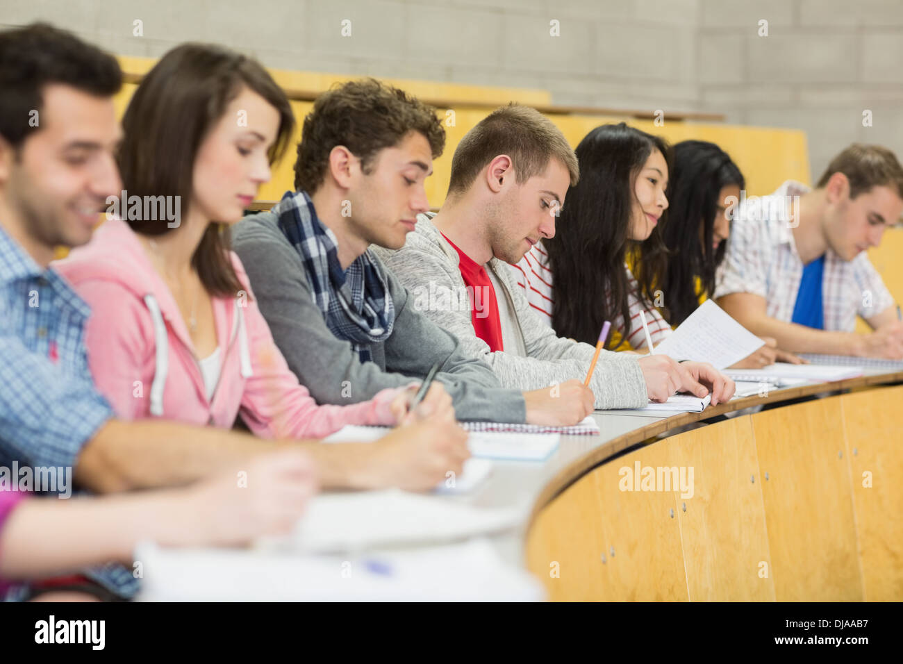 Students writing notes in a row at the lecture hall Stock Photo - Alamy