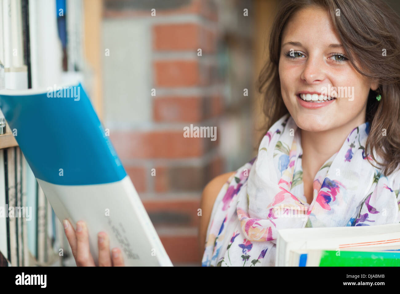Female student with books by the shelf in library Stock Photo - Alamy