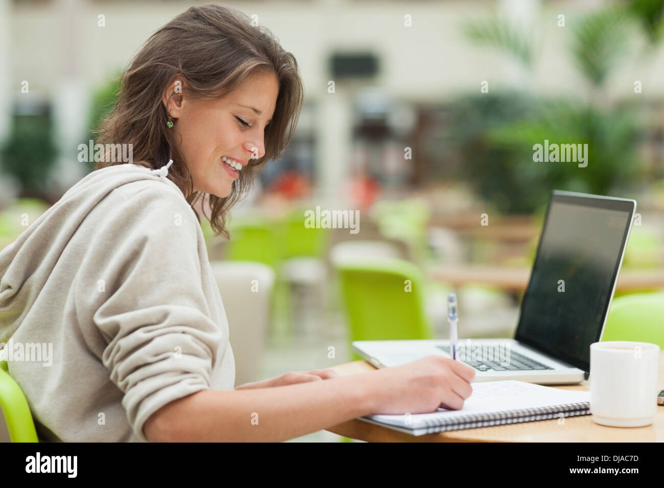 Student doing homework by laptop at cafeteria table Stock Photo - Alamy
