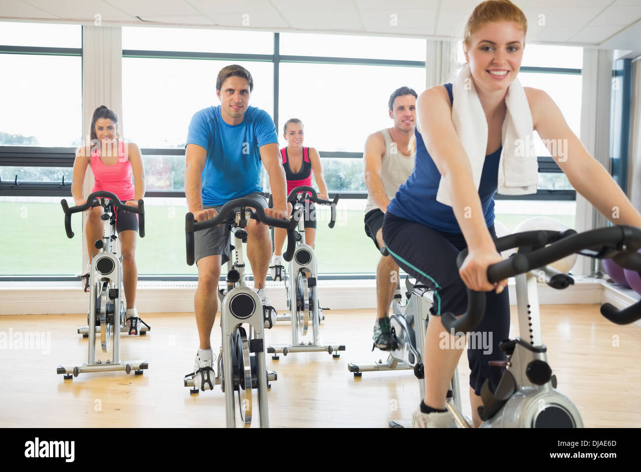 Happy woman teaches spinning class to four people Stock Photo - Alamy