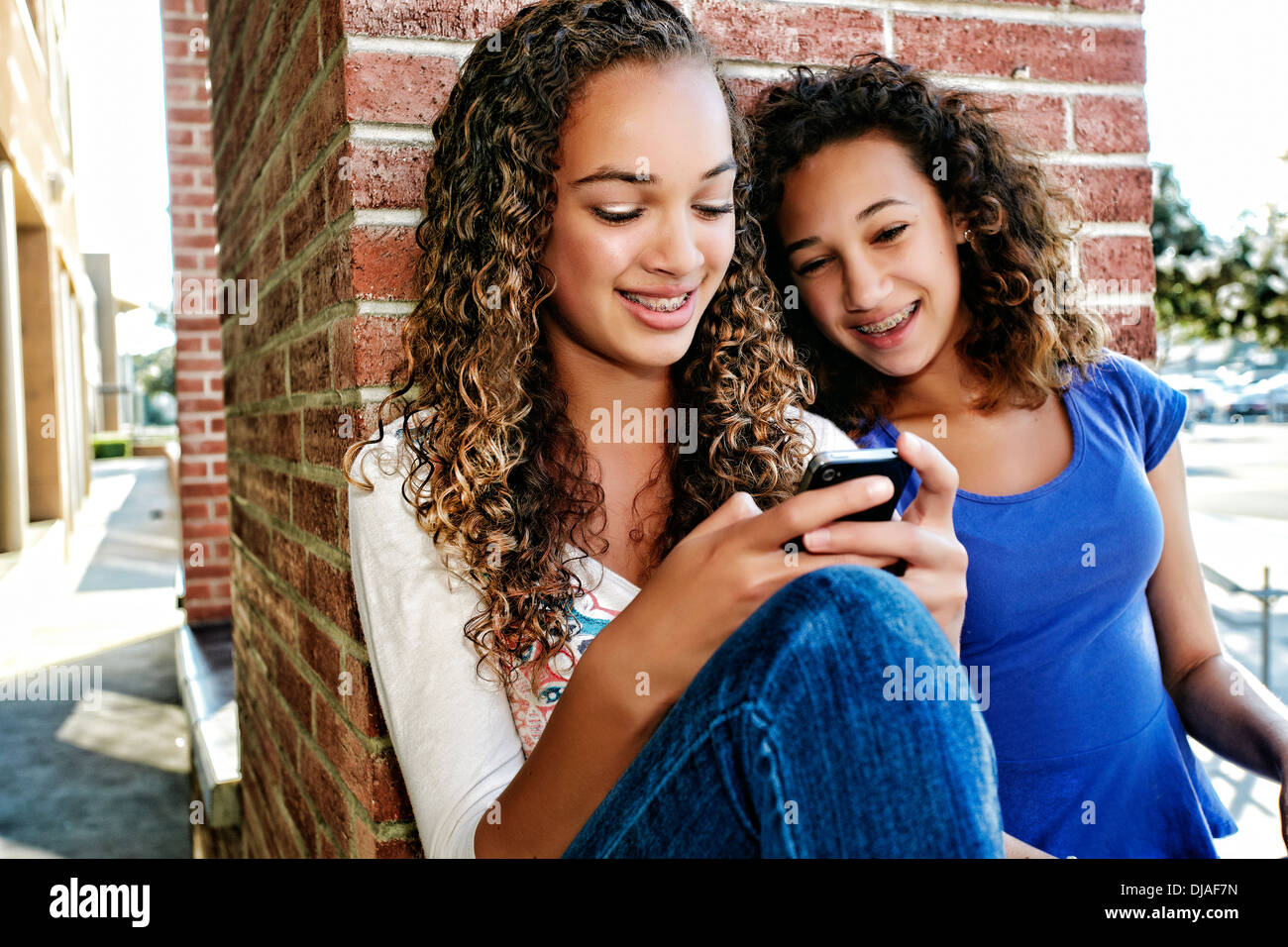 Mixed race girls using cell phone outdoors Stock Photo - Alamy