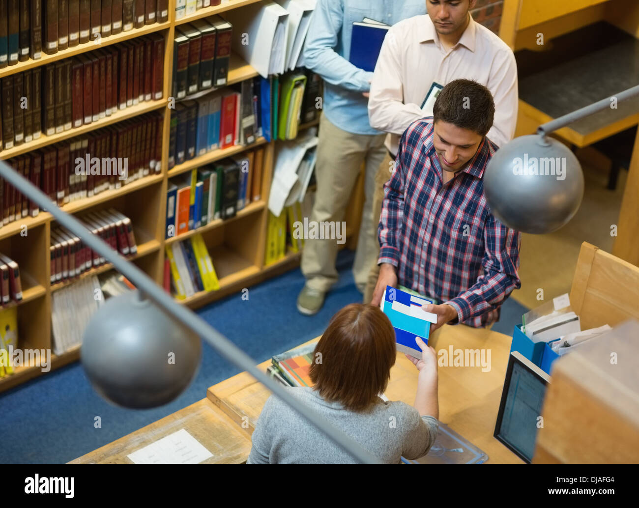Mature students at counter in college library Stock Photo - Alamy