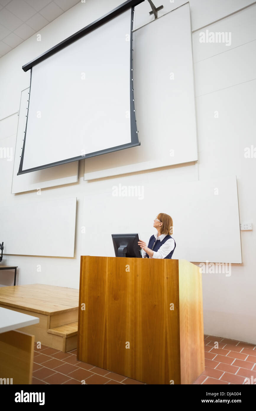 Teacher with computer and projection screen in lecture hall Stock Photo ...