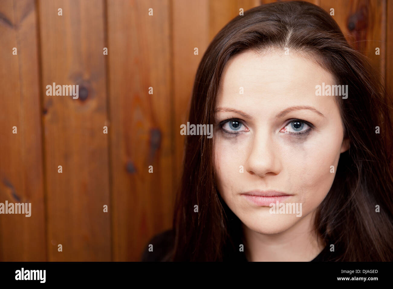 Upset looking young woman with her eye make-up running down her face ...