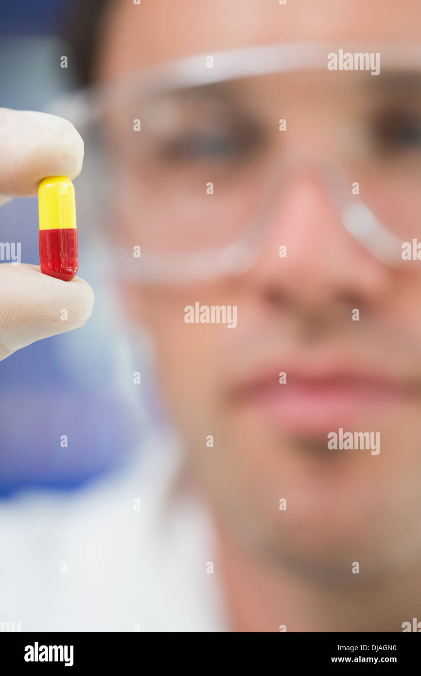 Extreme close-up of a male scientist analyzing a pill in the laboratory ...