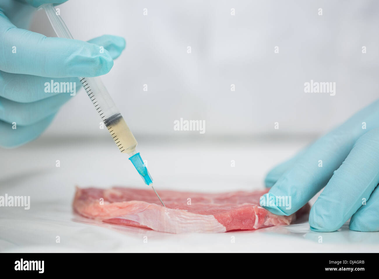 Close up of gloved researchers hands injecting meat Stock Photo - Alamy