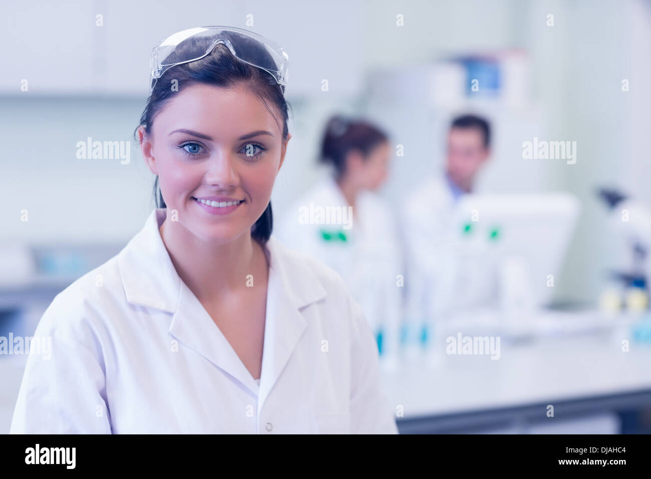 Female researcher with colleagues in background at lab Stock Photo - Alamy
