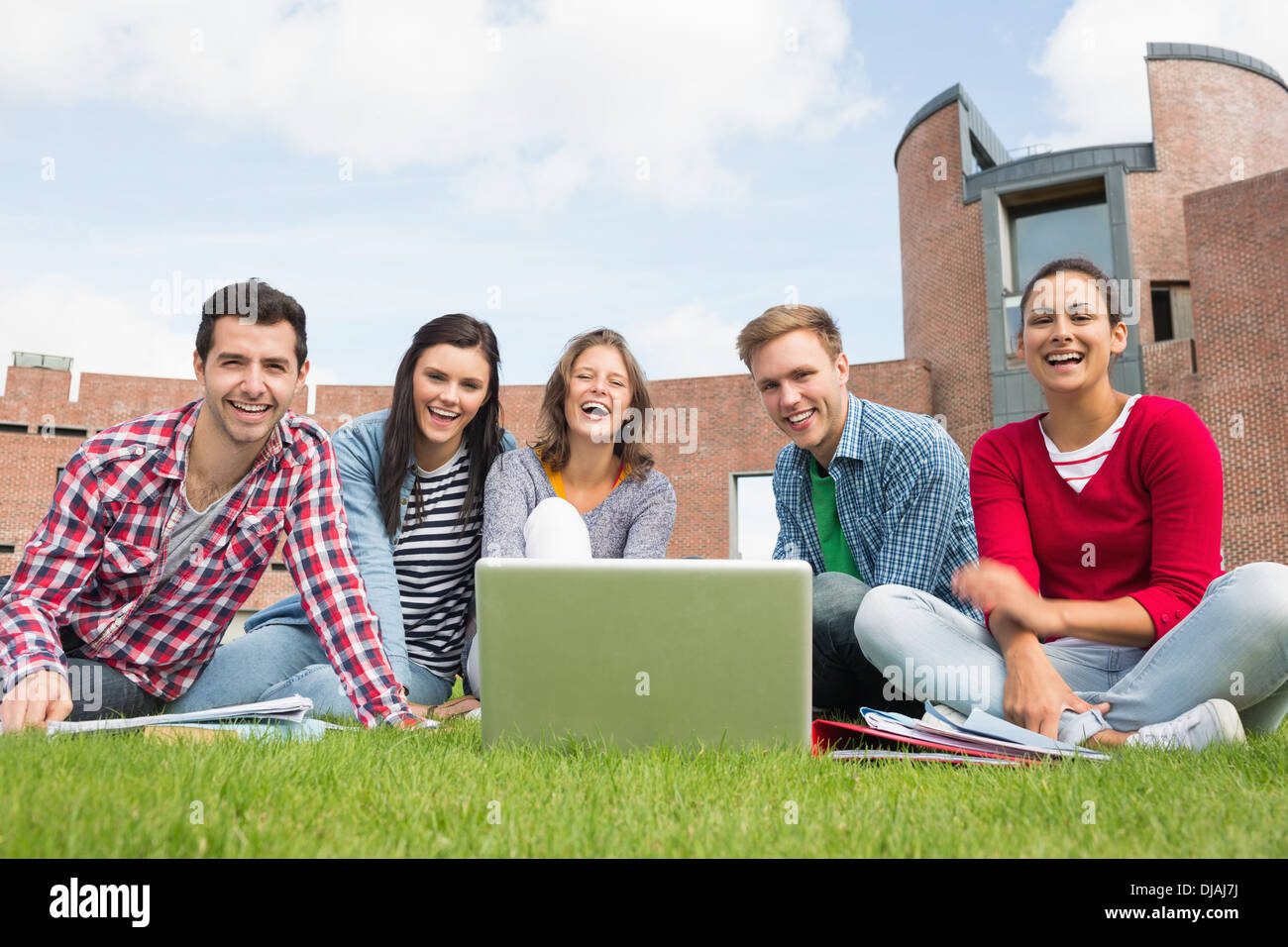Students with laptop in the lawn against college building Stock Photo ...