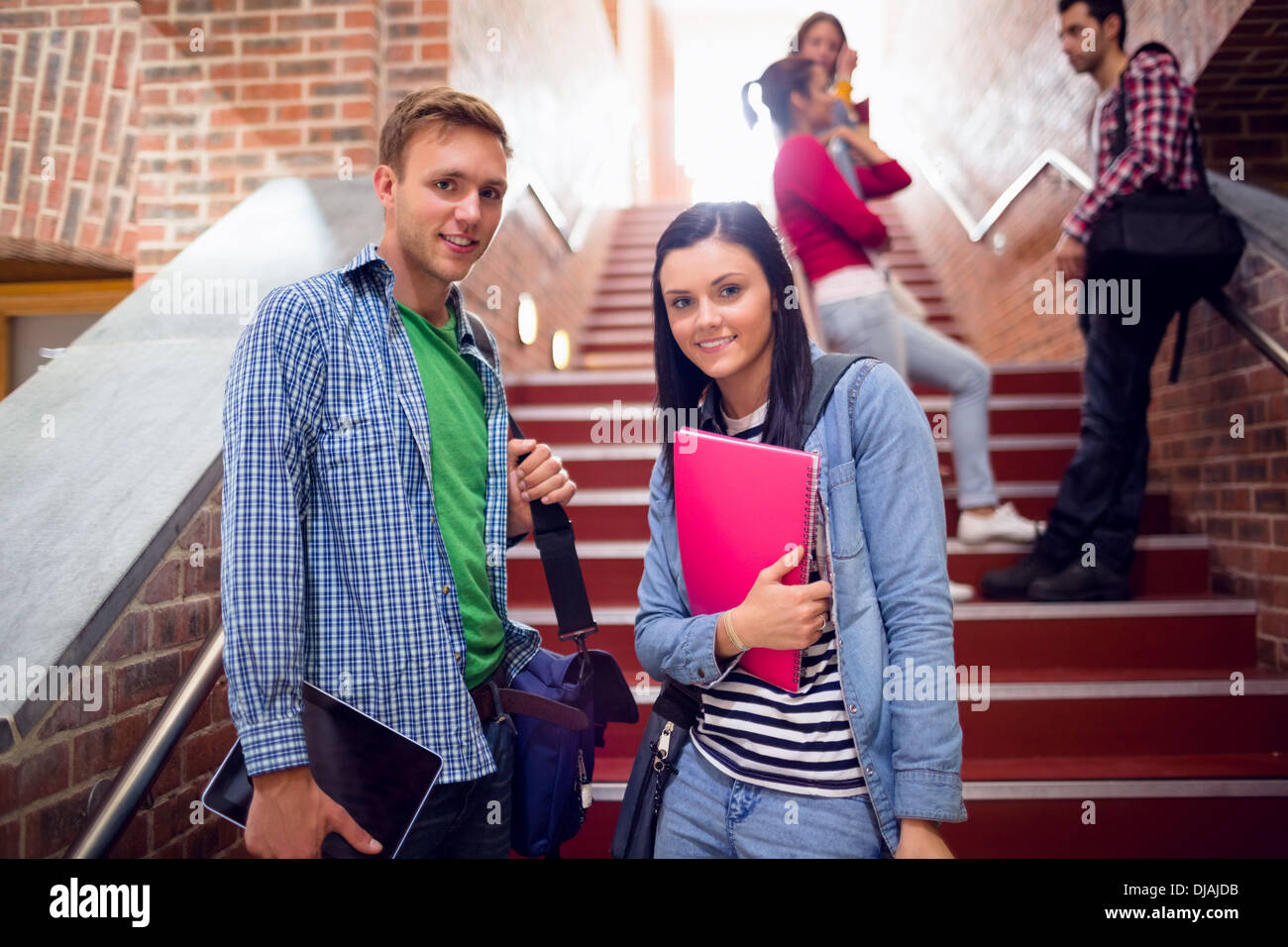 Couple with students behind on stairs in the college Stock Photo - Alamy