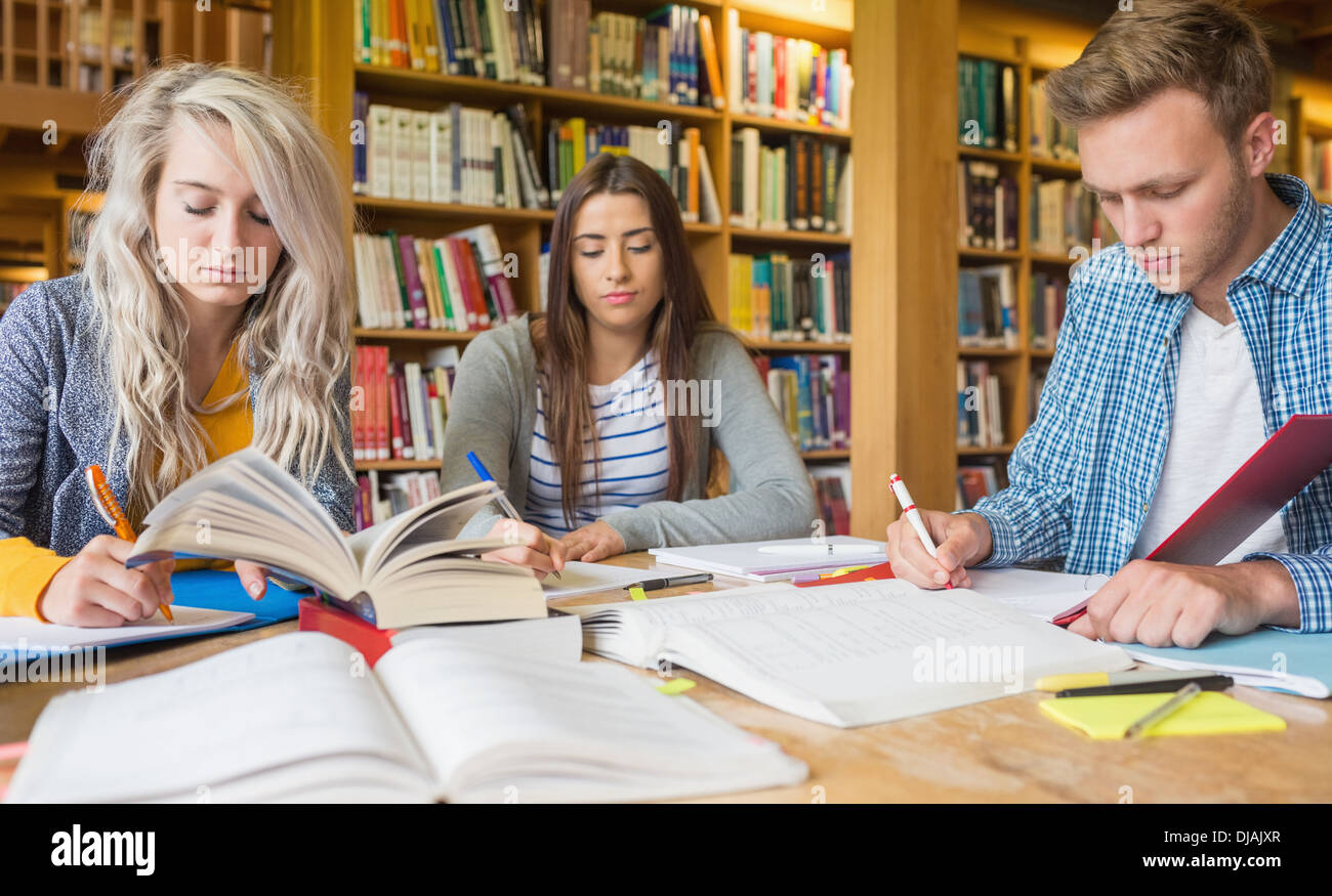 Students writing notes at library desk Stock Photo - Alamy