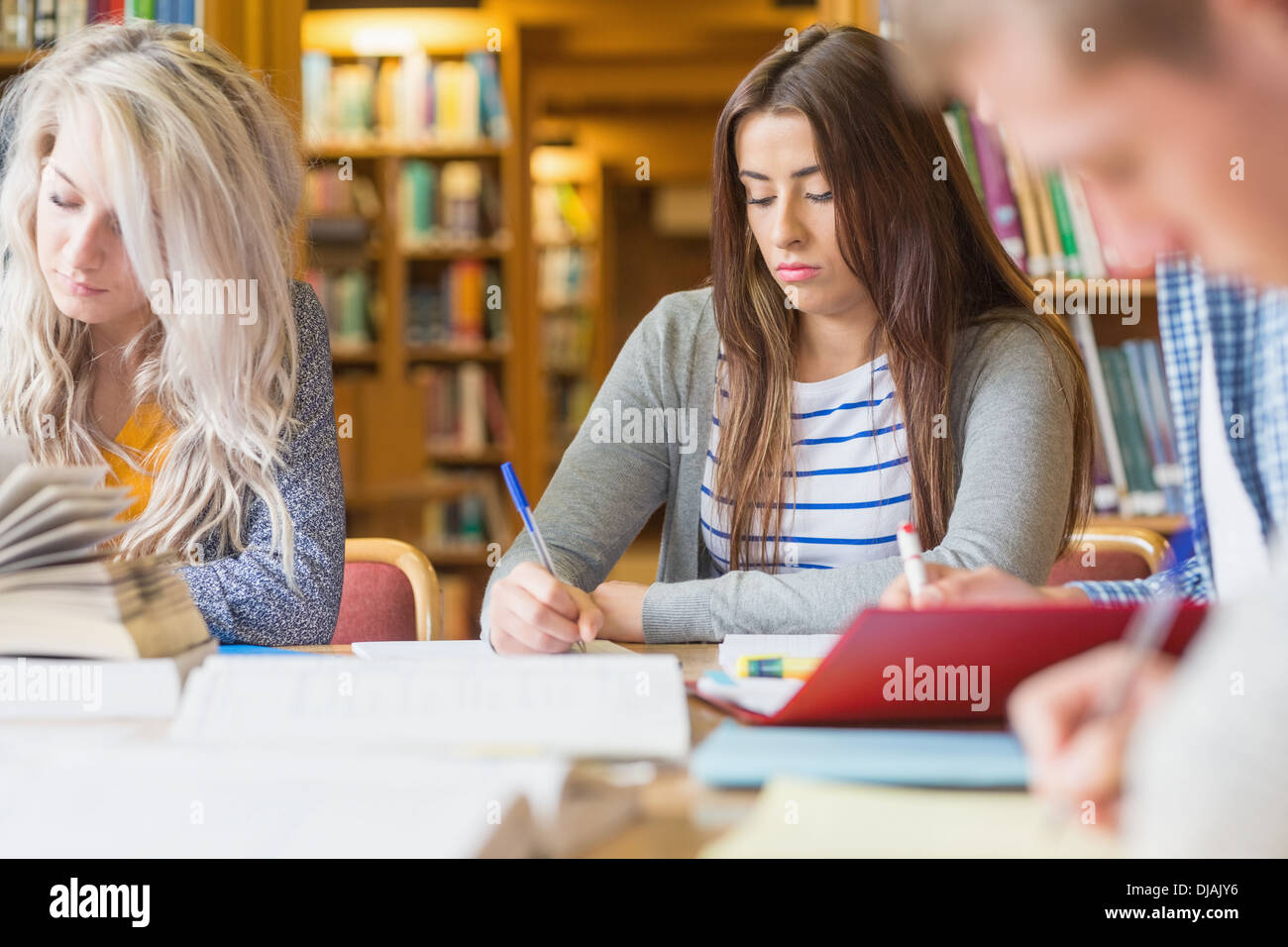 Students writing notes at library desk Stock Photo - Alamy