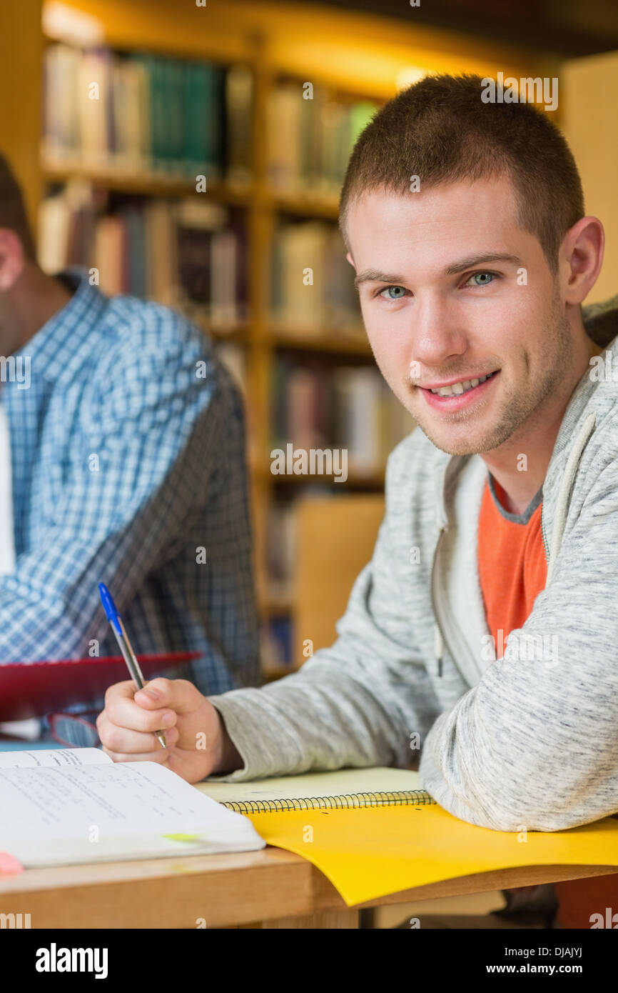 Portrait of a smiling male student at library desk Stock Photo - Alamy