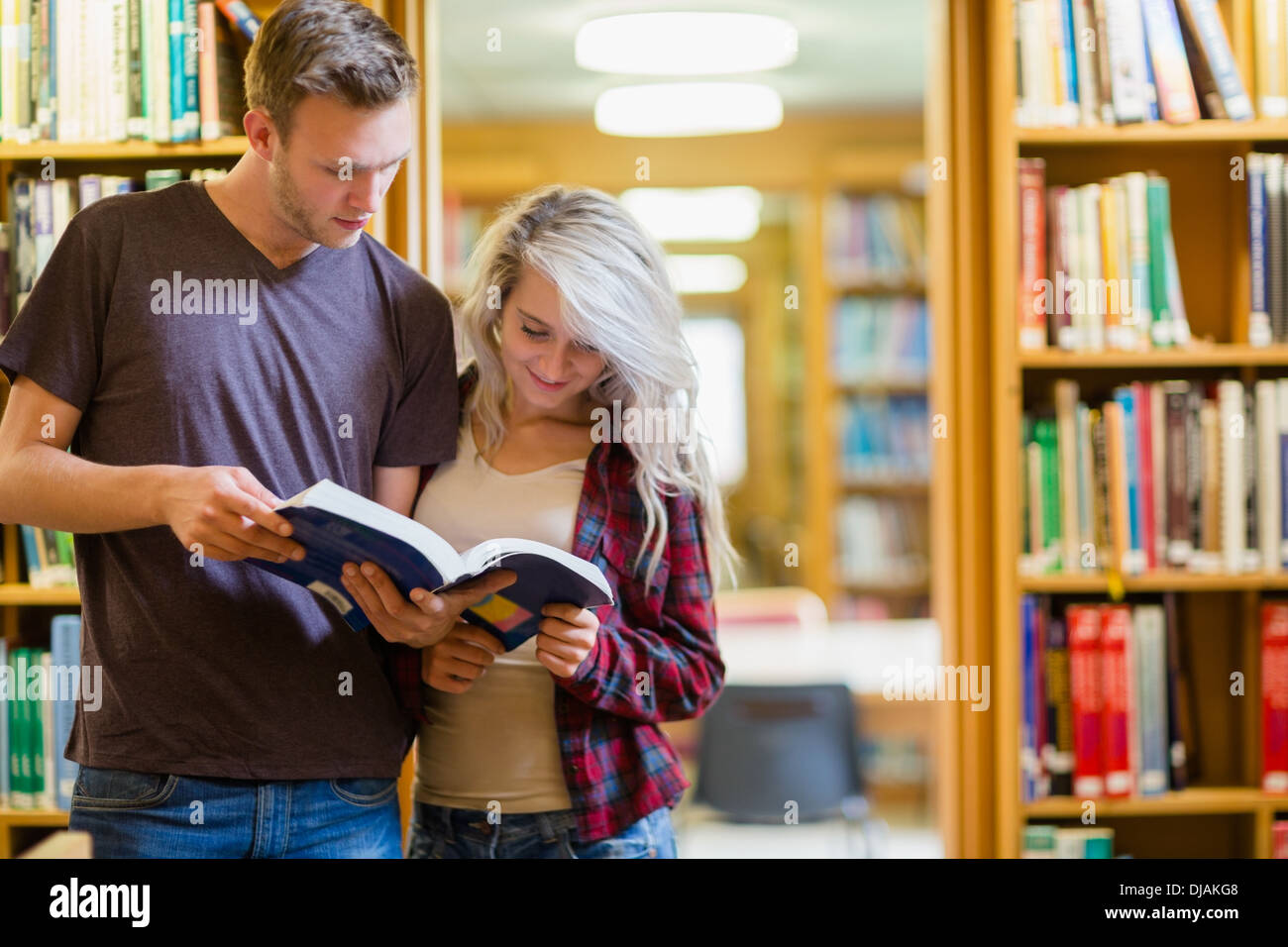 Two young students reading book in the library Stock Photo - Alamy