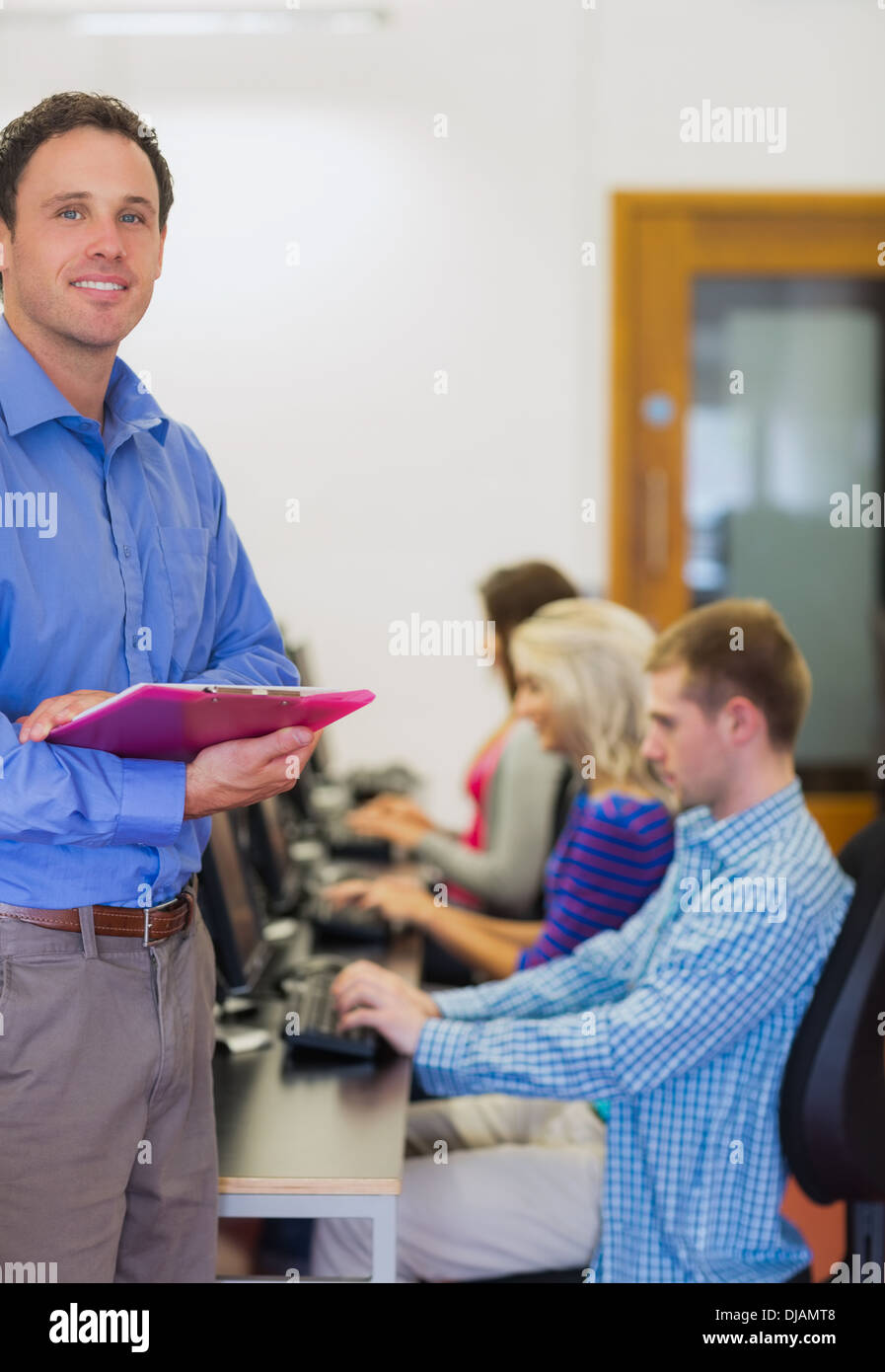 Teacher with students using computers in computer room Stock Photo - Alamy