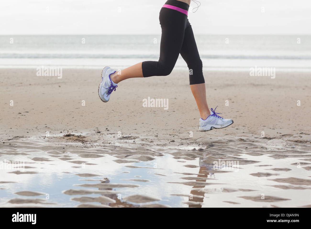 Low section of healthy woman jogging on beach Stock Photo - Alamy
