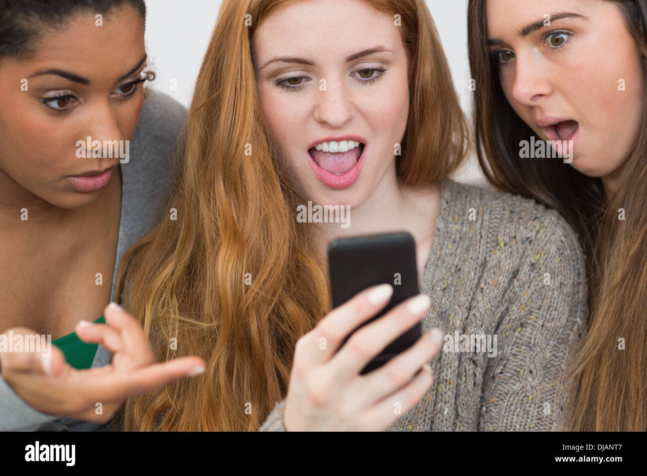 Shocked female friends looking at mobile phone together Stock Photo - Alamy