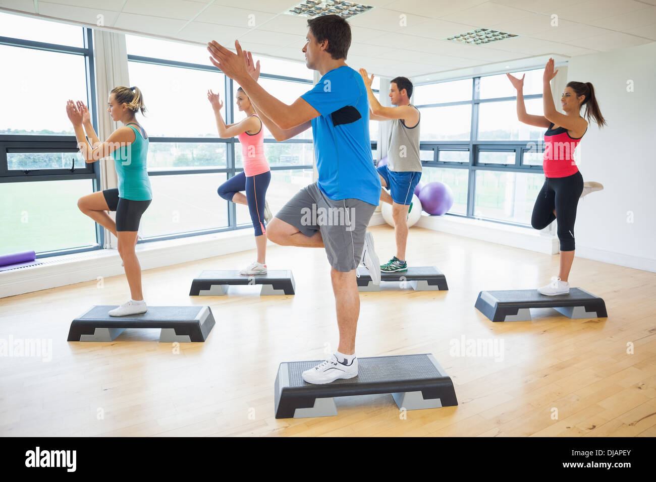 Instructor with fitness class performing step aerobics exercise Stock ...