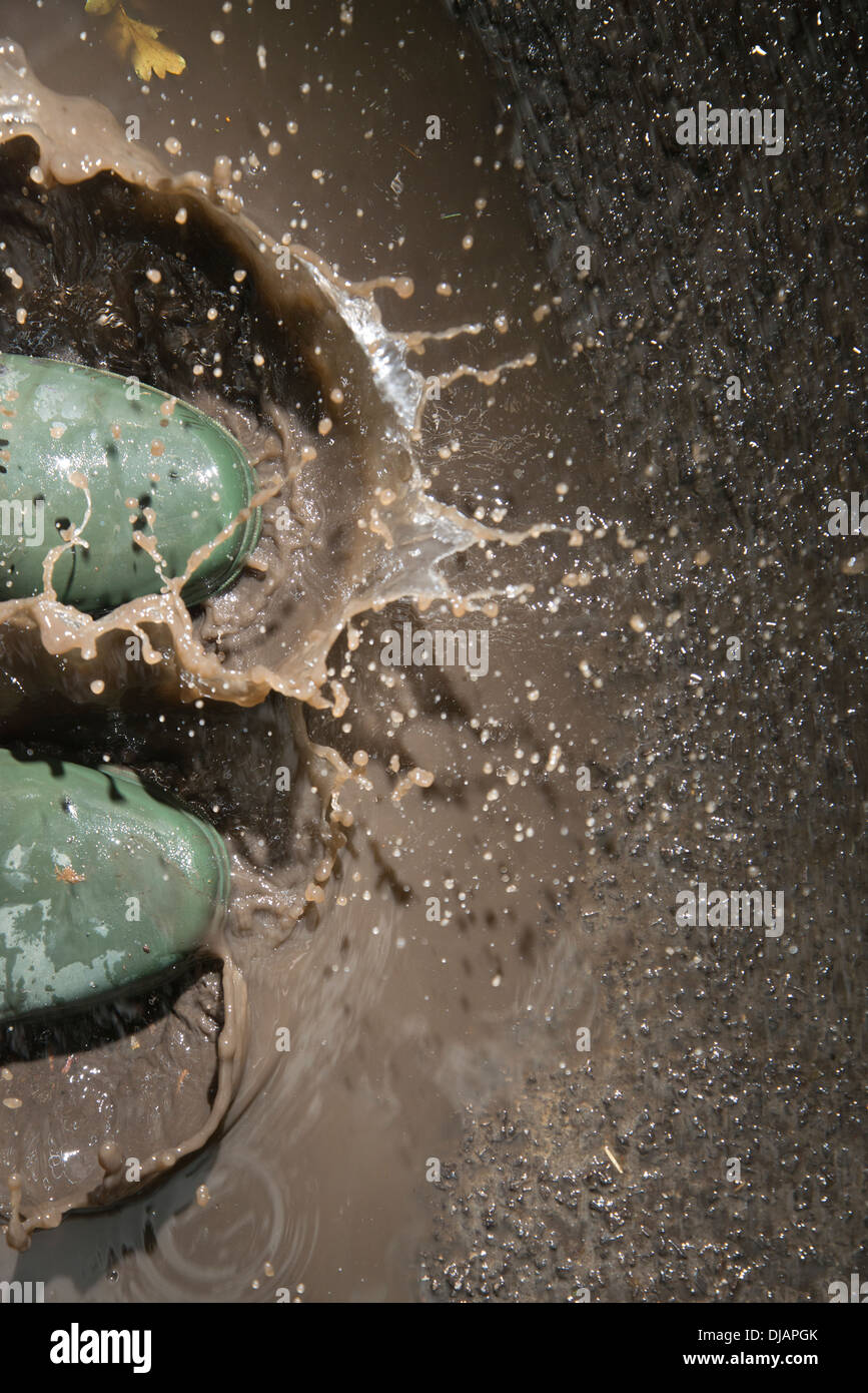 Splashing boots in muddy puddles of water Stock Photo - Alamy