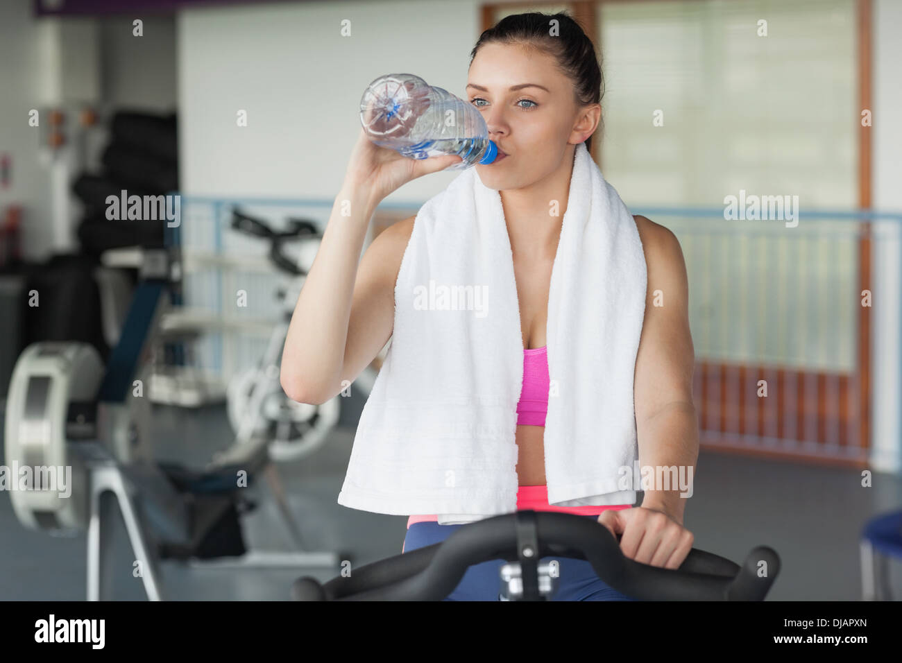 Tired woman drinking water while working out at spinning class Stock ...