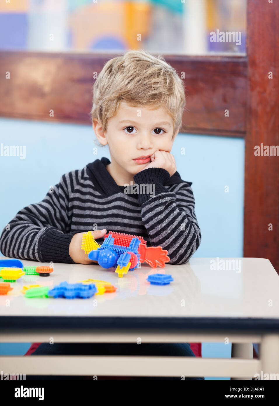 Bored Boy Holding Blocks Sitting At Desk In Classroom Stock Photo - Alamy