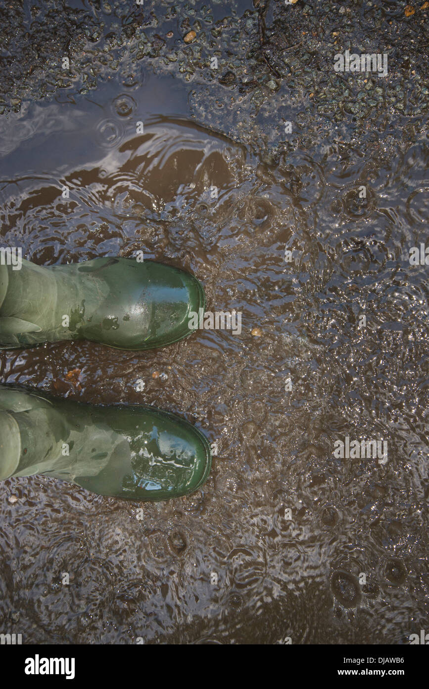 Splashing boots in muddy puddles of water Stock Photo - Alamy