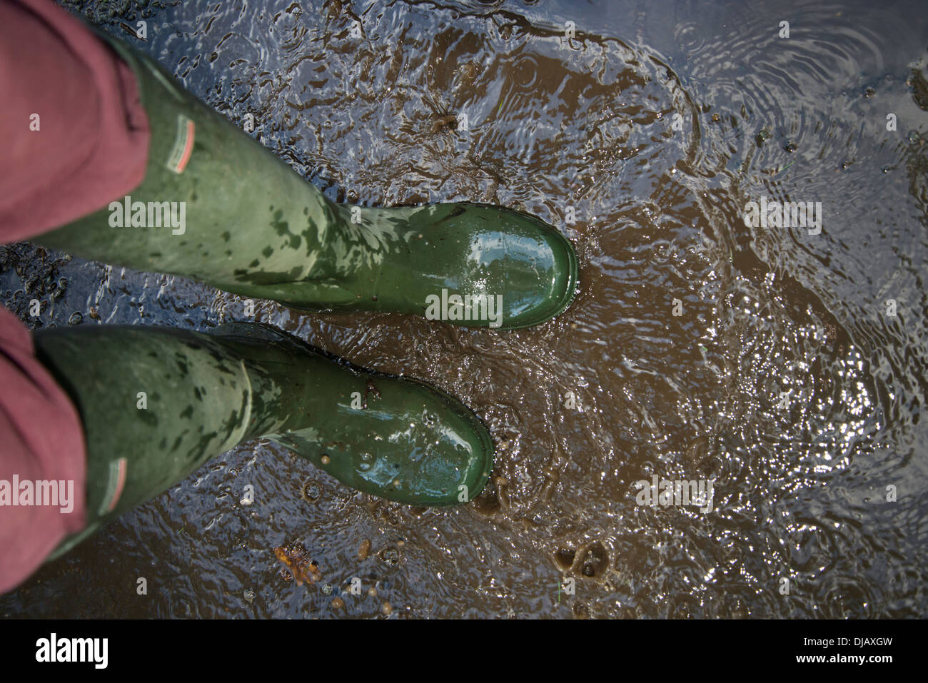 Splashing boots in muddy puddles of water Stock Photo - Alamy