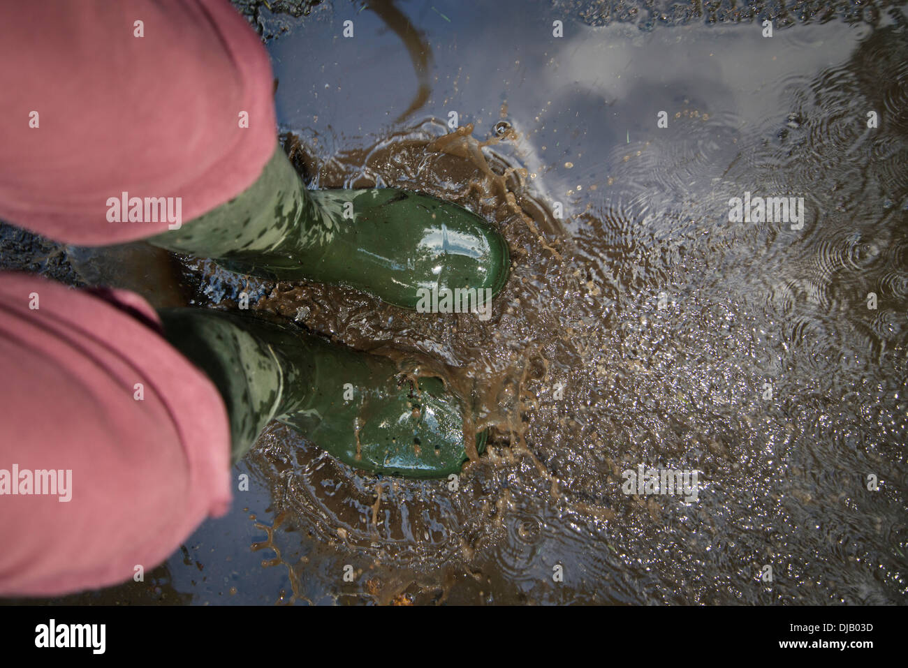 Splashing boots in muddy puddles of water Stock Photo - Alamy