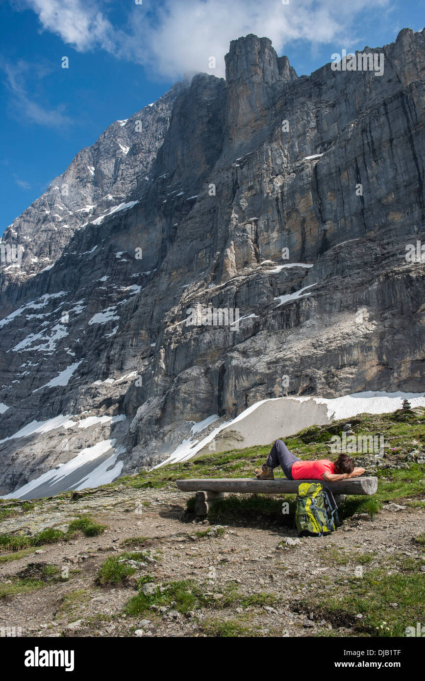 A hiker lying on a bench on the Eiger Trail, behind the Eiger North ...