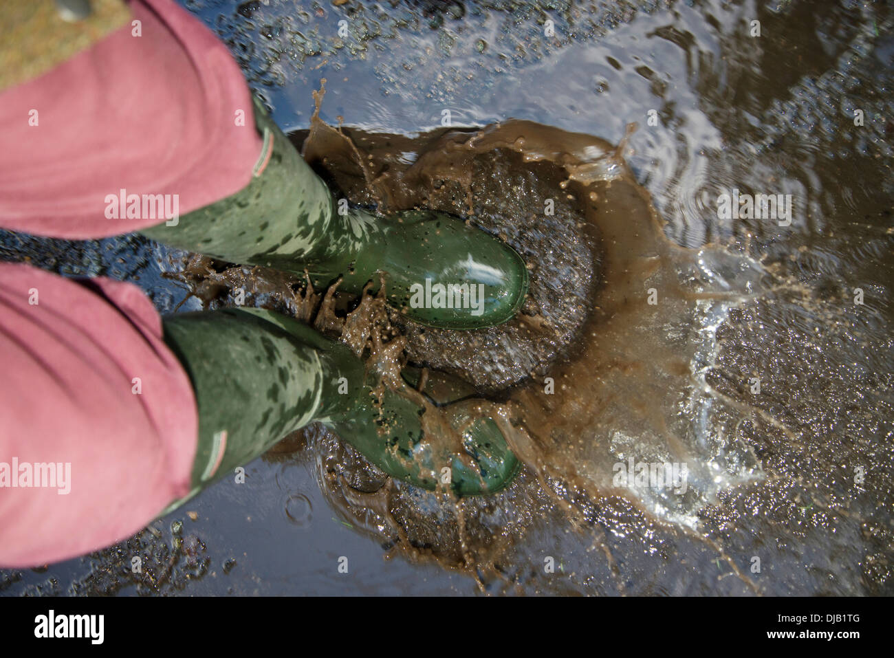 Splashing boots in muddy puddles of water Stock Photo - Alamy