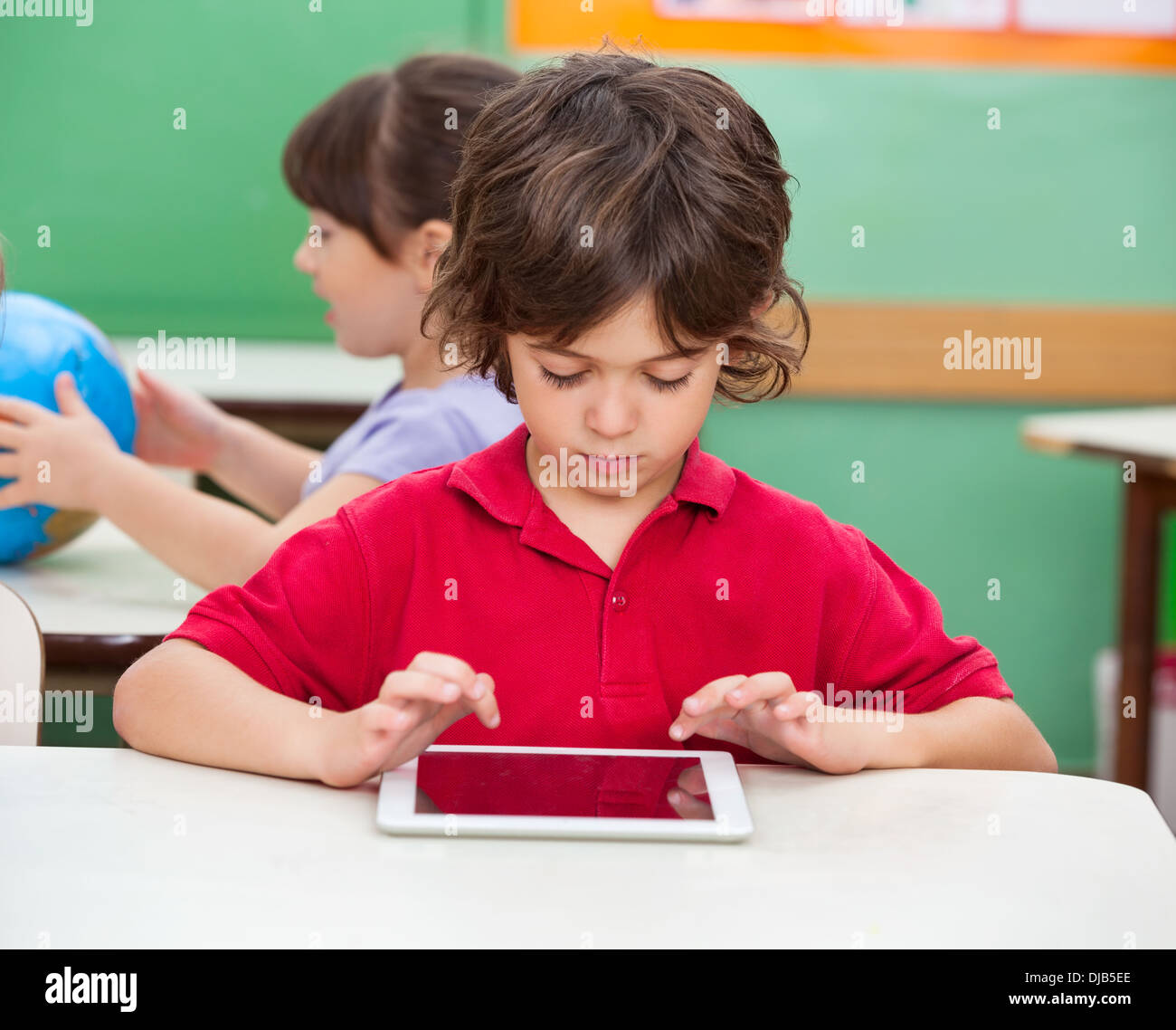 Boy Using Digital Tablet At Desk Stock Photo - Alamy