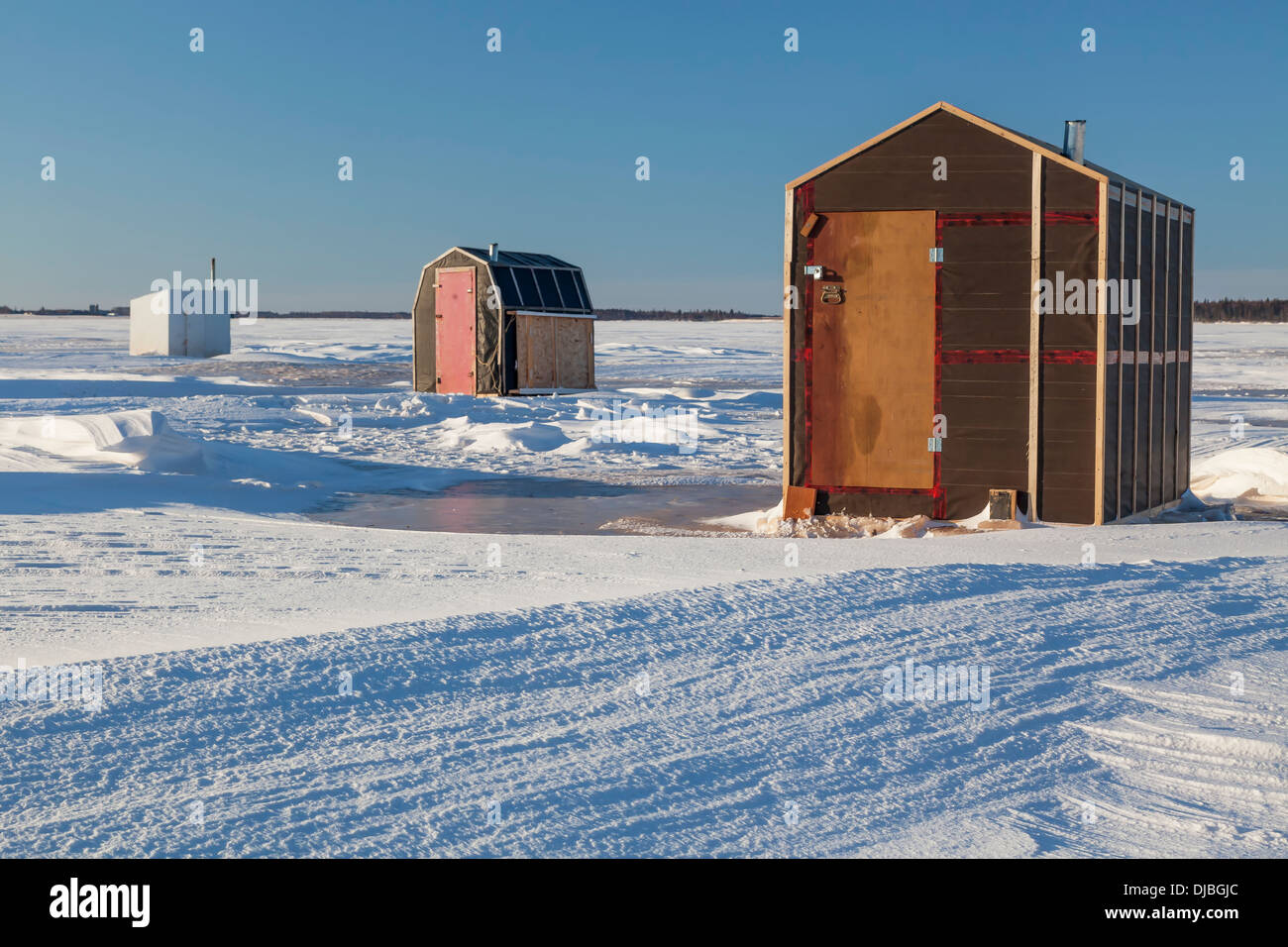 Rustic ice fishing shacks out on the ice on the shoreline of Prince ...