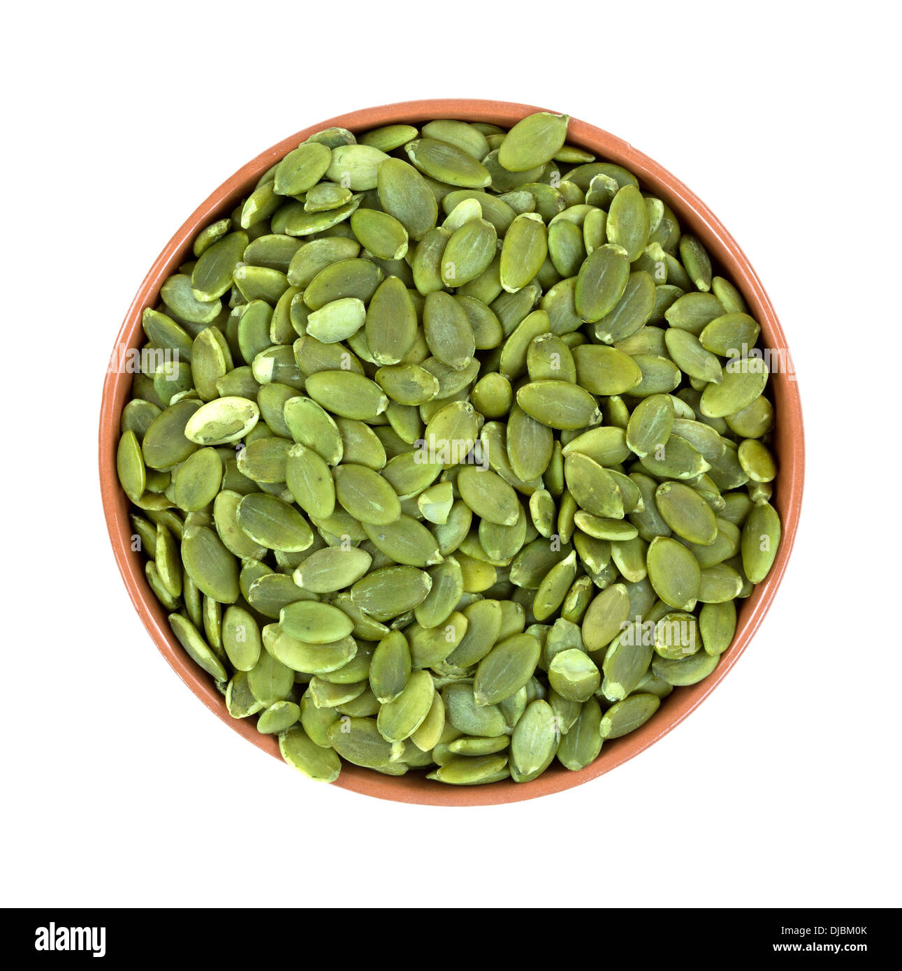 Top view of a small bowl filled with green pepitas on a white ...