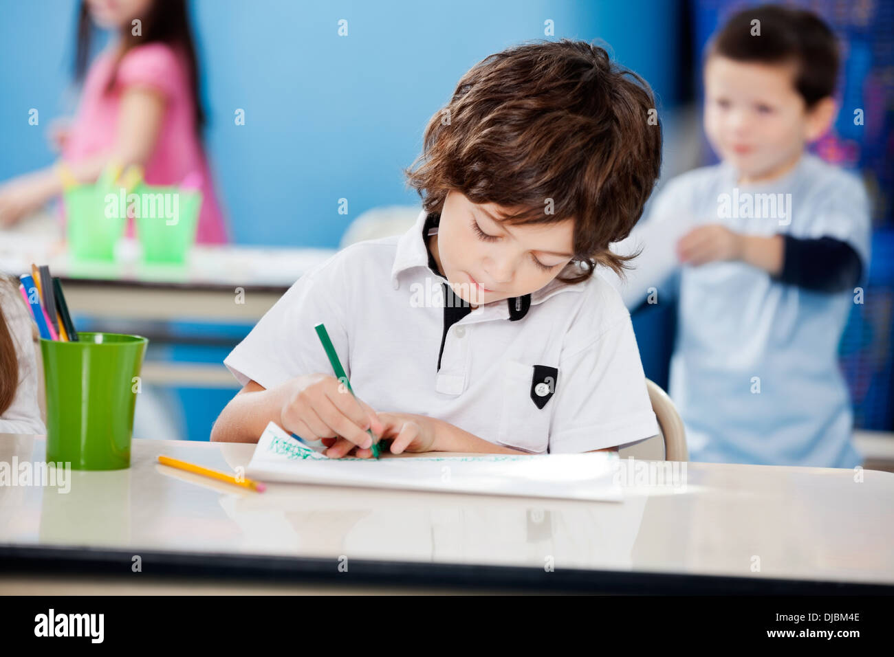 Boy Drawing With Sketch Pen At Desk In Kindergarten Stock Photo - Alamy
