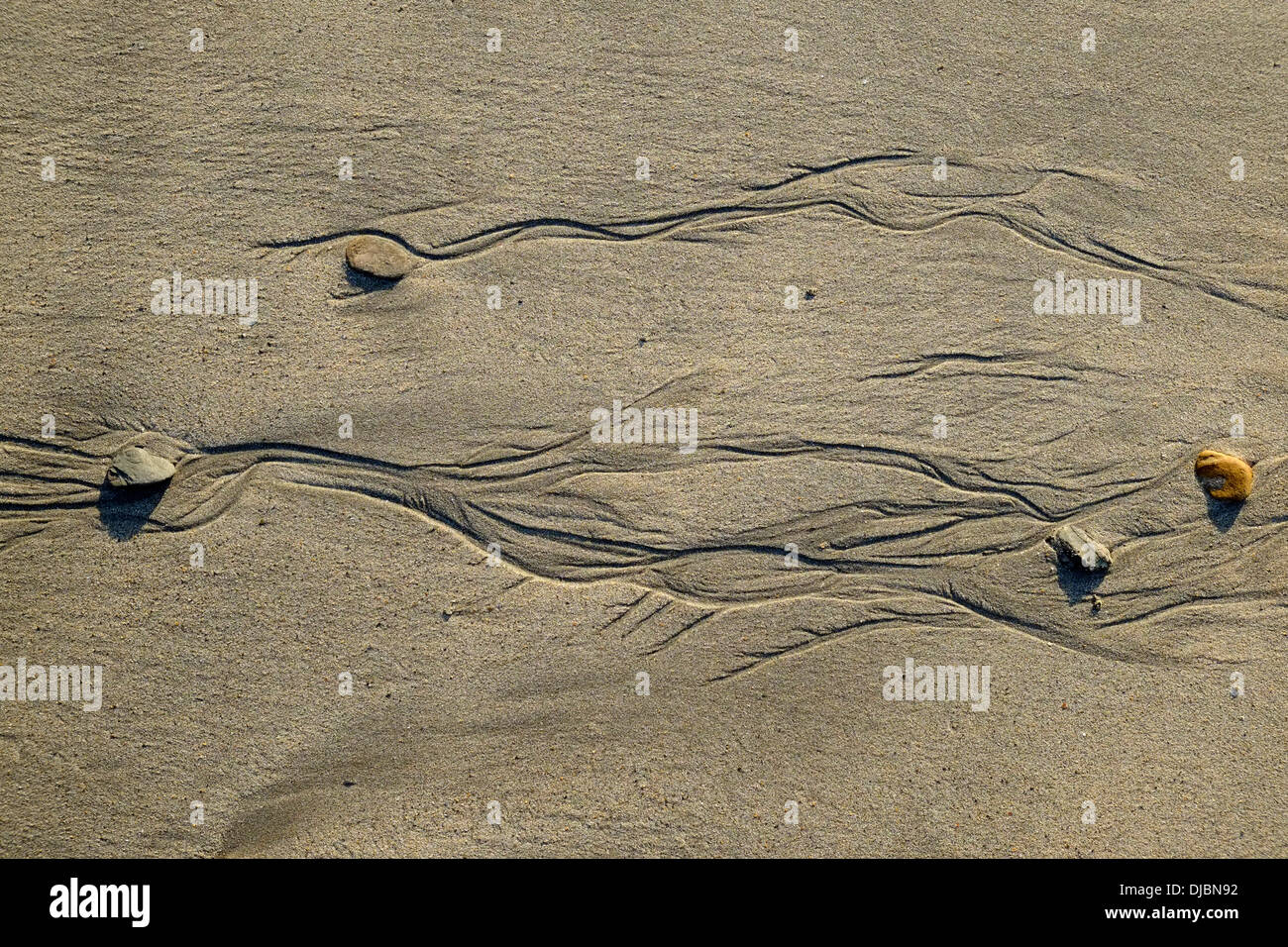 Close-up background of sandy rivulets and pebbles on a beach at low ...