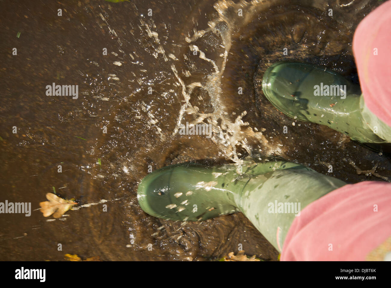 Splashing boots in muddy puddles of water Stock Photo - Alamy