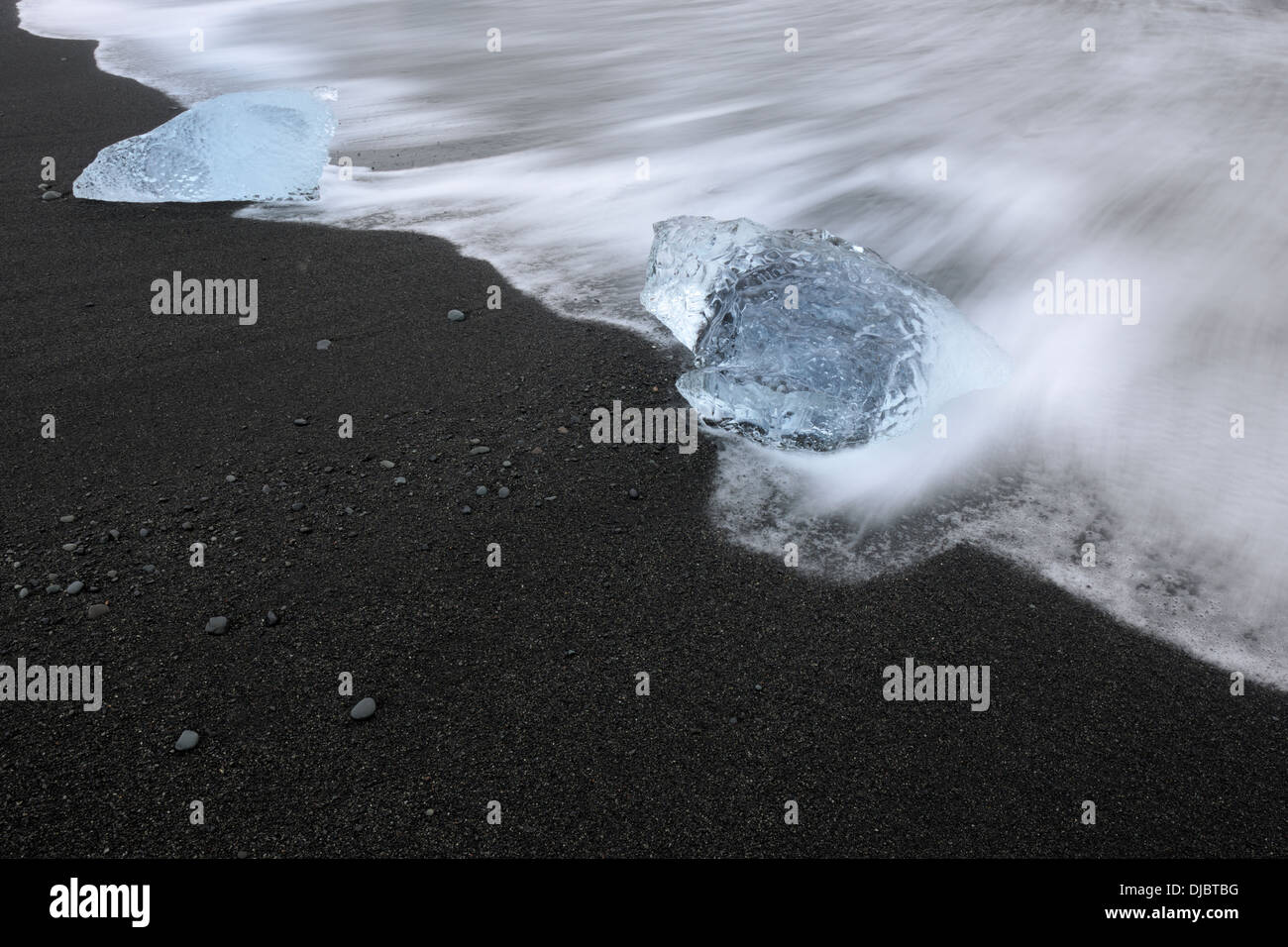 Ice block on a beach with lava stones and water floating over Stock ...