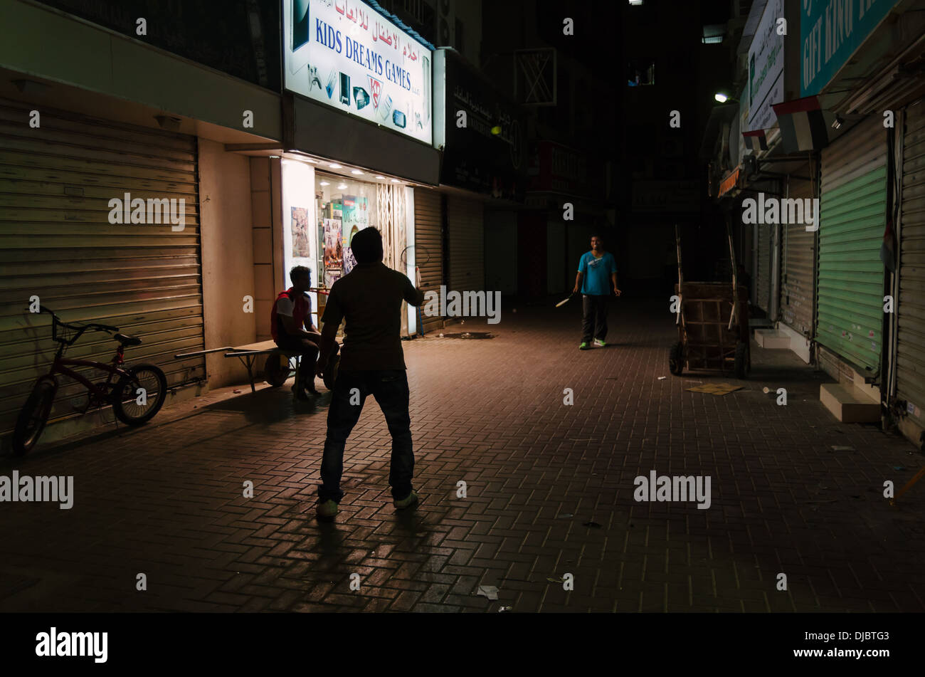 Two salesman playing badminton outside their store in a dark alley at ...