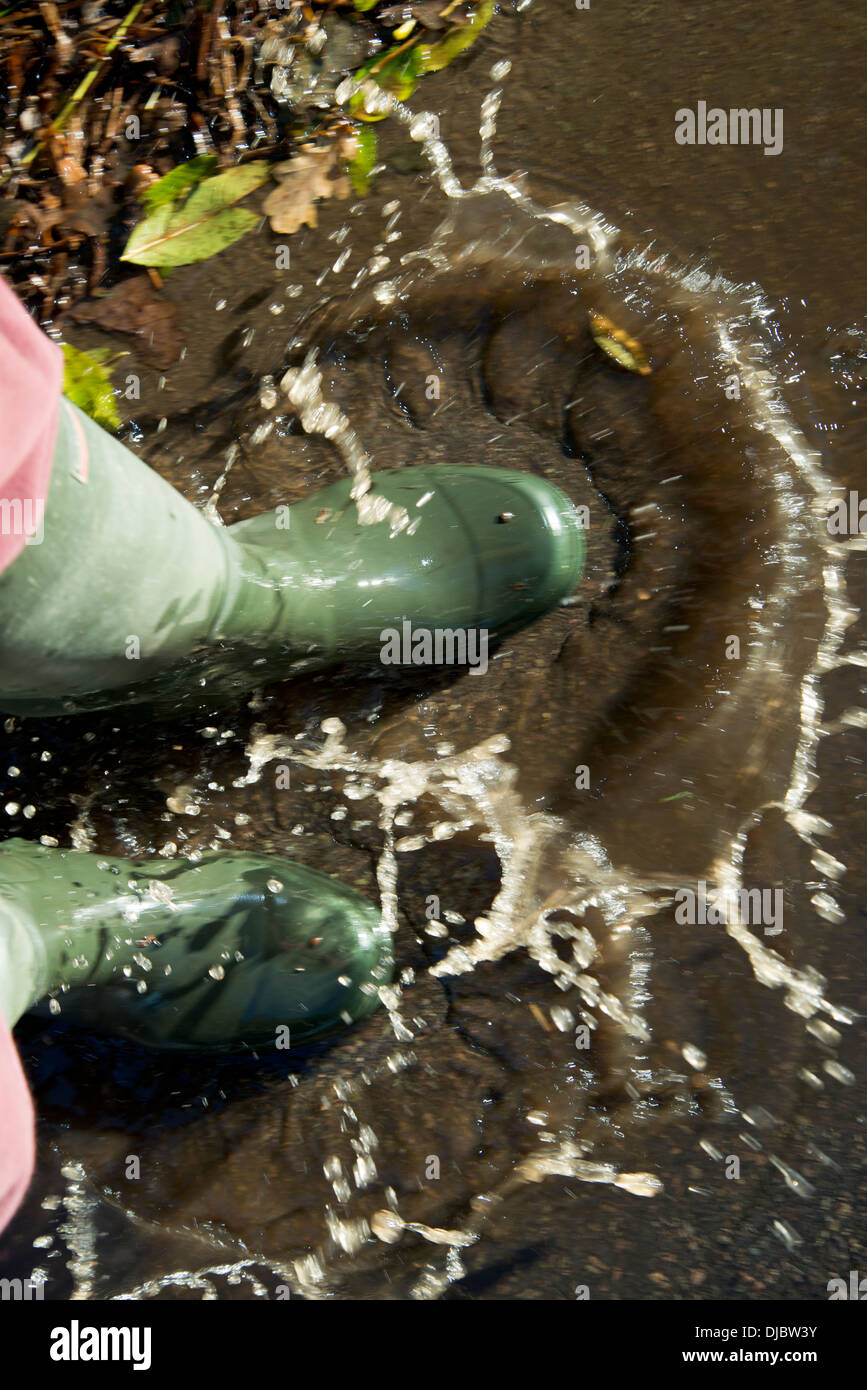 Splashing boots in muddy puddles of water Stock Photo - Alamy