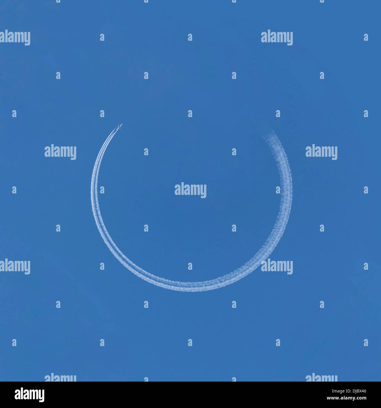 Airplane making circle trace against clear blue sky Stock Photo - Alamy